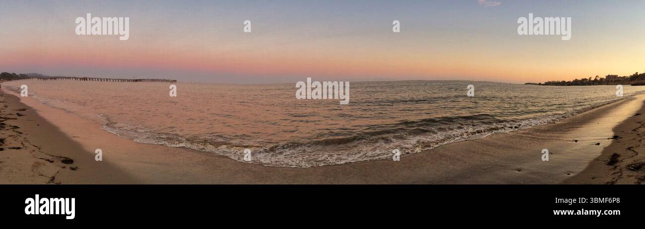 A peaceful beach scene captured in a panoramic view during sunset ...