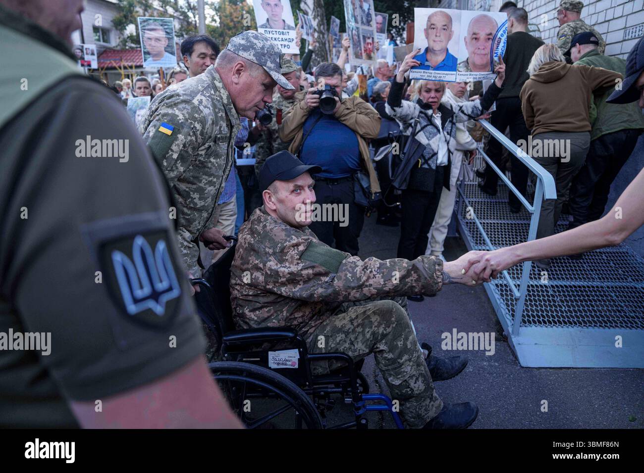 A Ukrainian serviceman uses a wheelchair to move his comrade from an ...