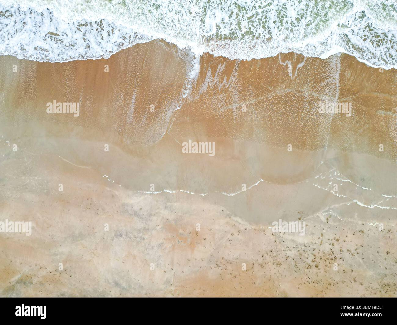 This image features a peaceful sandy beach with light brown sand ...