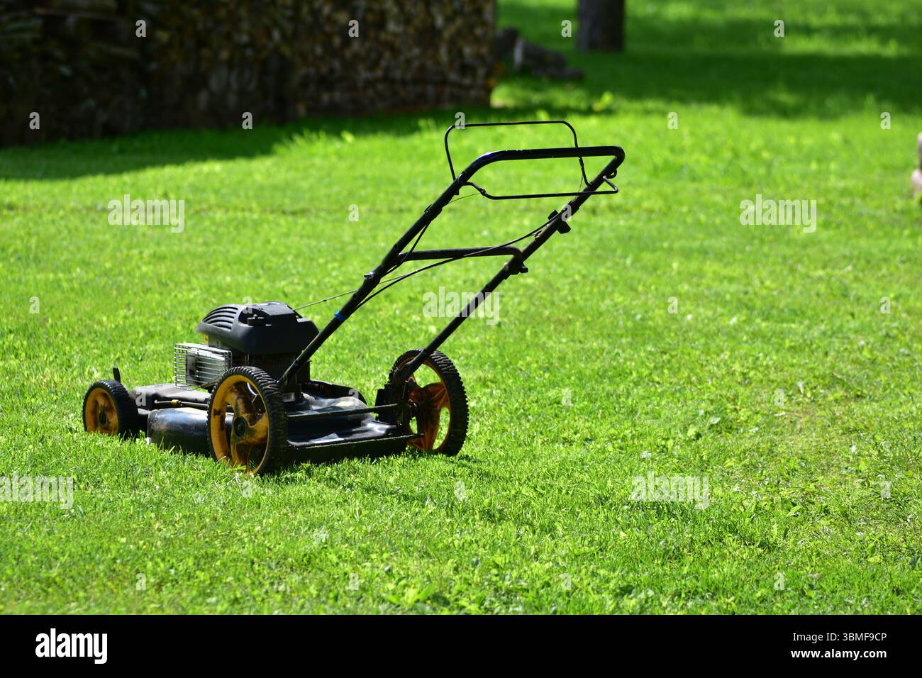 Old gasoline push lawn mower standing on freshly cut green grass ...
