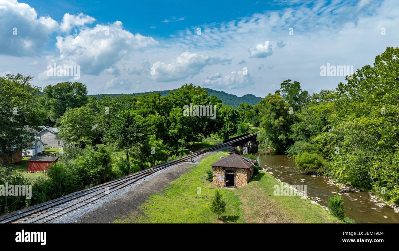 A tranquil view showcases railway tracks running along a winding creek ...