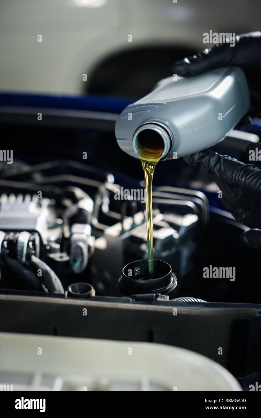 Worker pouring motor oil from bottle into car engine, closeup Stock ...