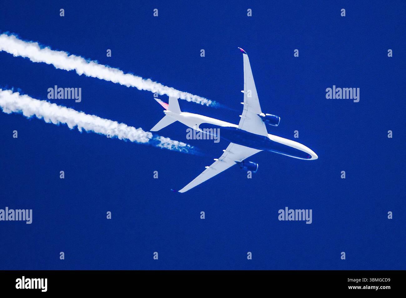 Sharp telephoto close-up of jet plane aircraft with contrails cruising ...