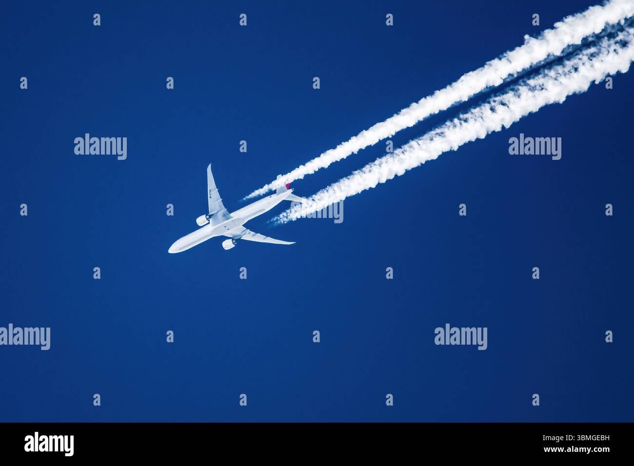 Sharp telephoto close-up of jet plane aircraft with contrails cruising ...