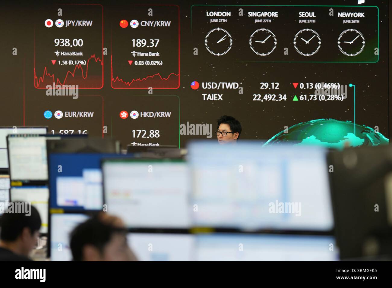 A dealer walks past near screens showing the foreign exchange rates at ...