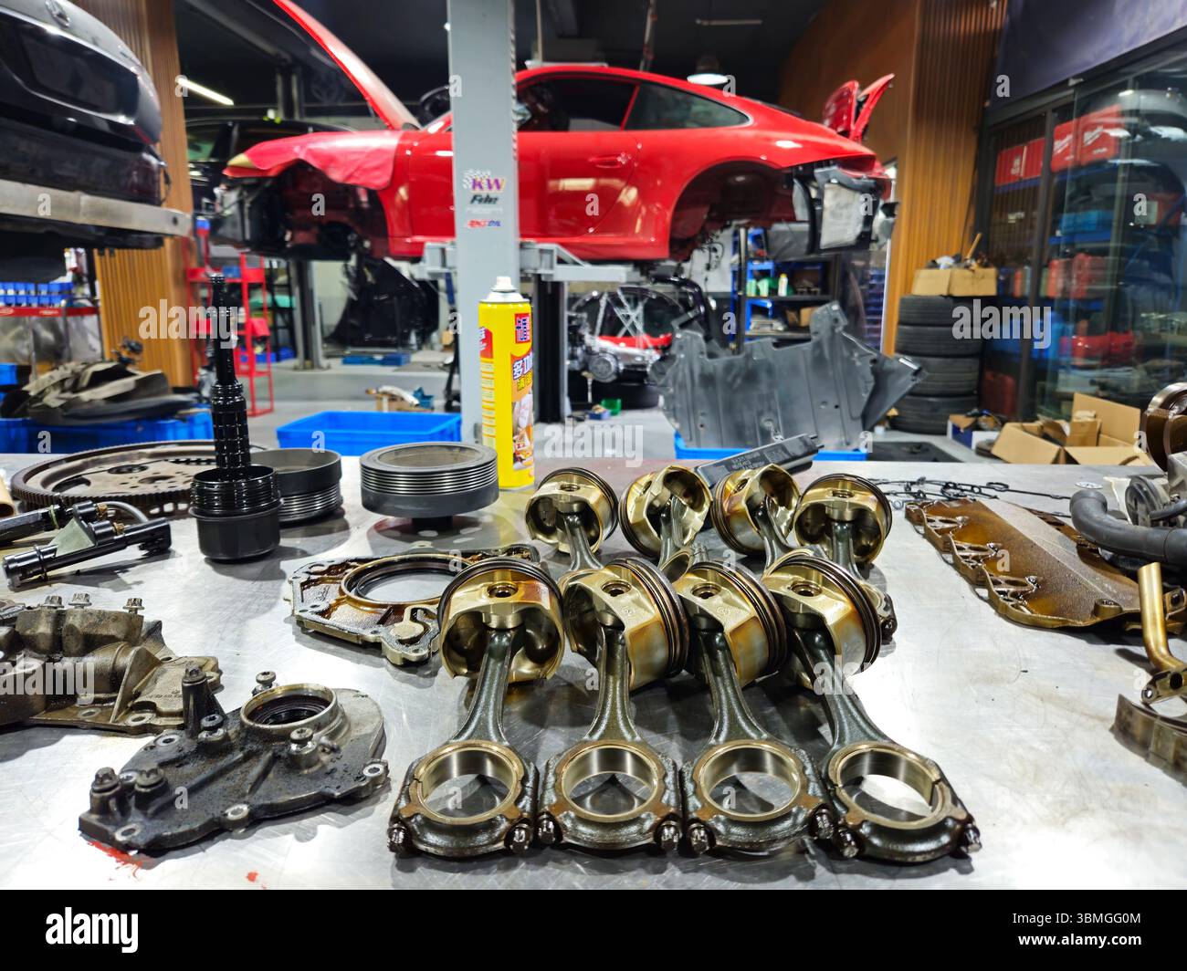 Porsche 911 in Background of Disassembled Engine Pistons and Components ...