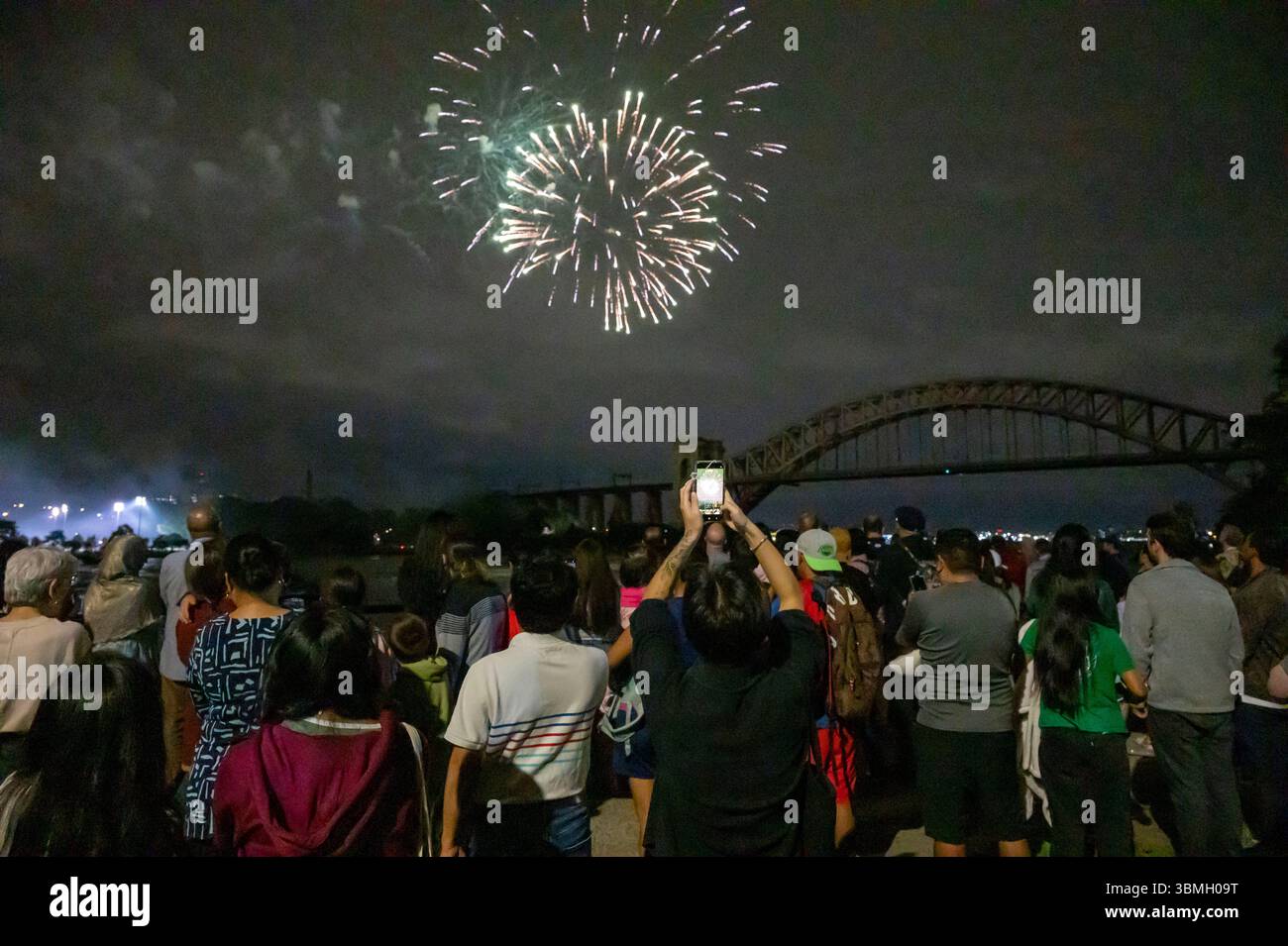 Spectators watch fireworks explode over the Hell Gate Bridge during the ...