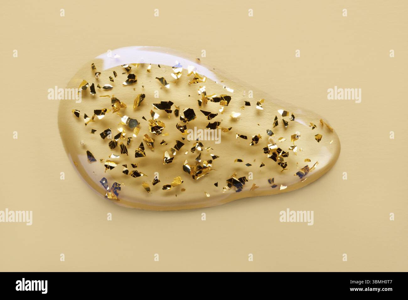 Transparent liquid gel swatch with gold particles on beige background ...