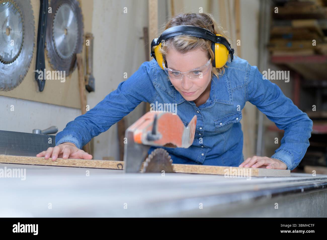 female carpenter wearing earmuffs and using a table saw Stock Photo - Alamy