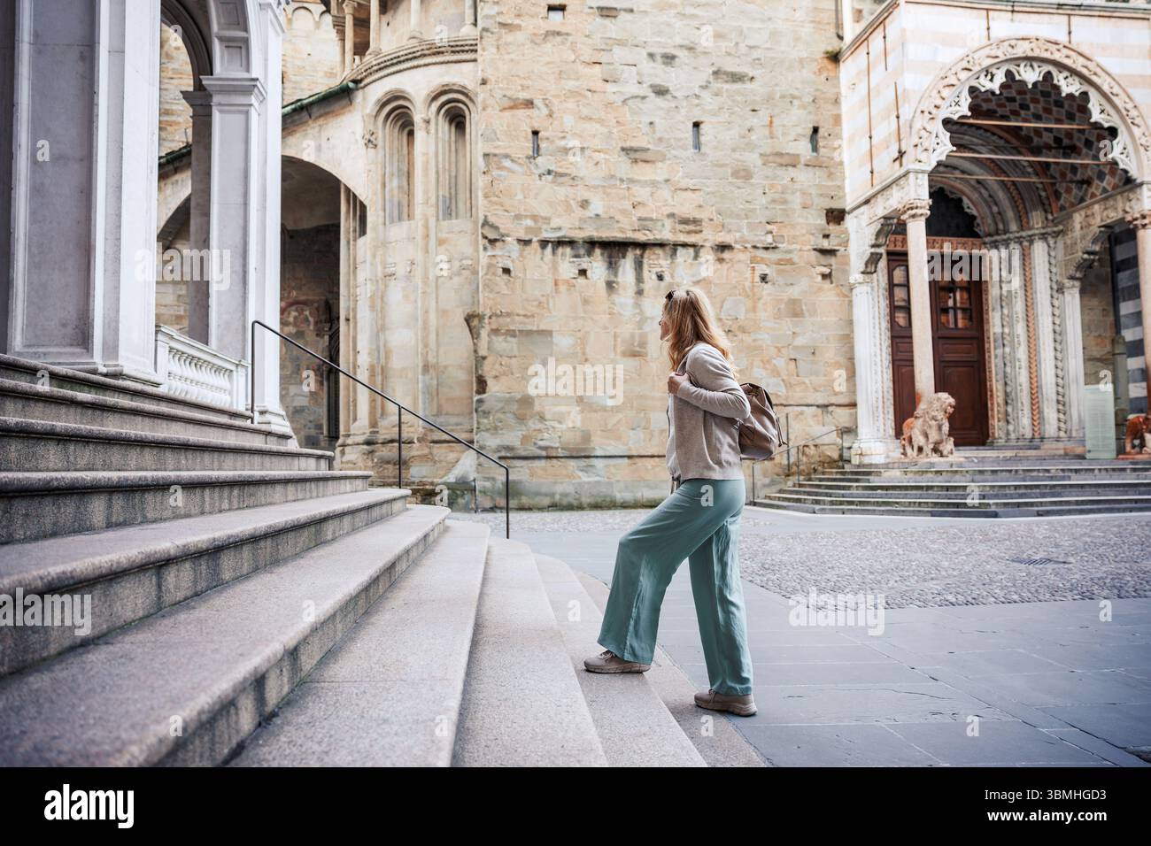 Woman exploring historic city Bergamo, Italy during solo summer vacation city walk experience ...