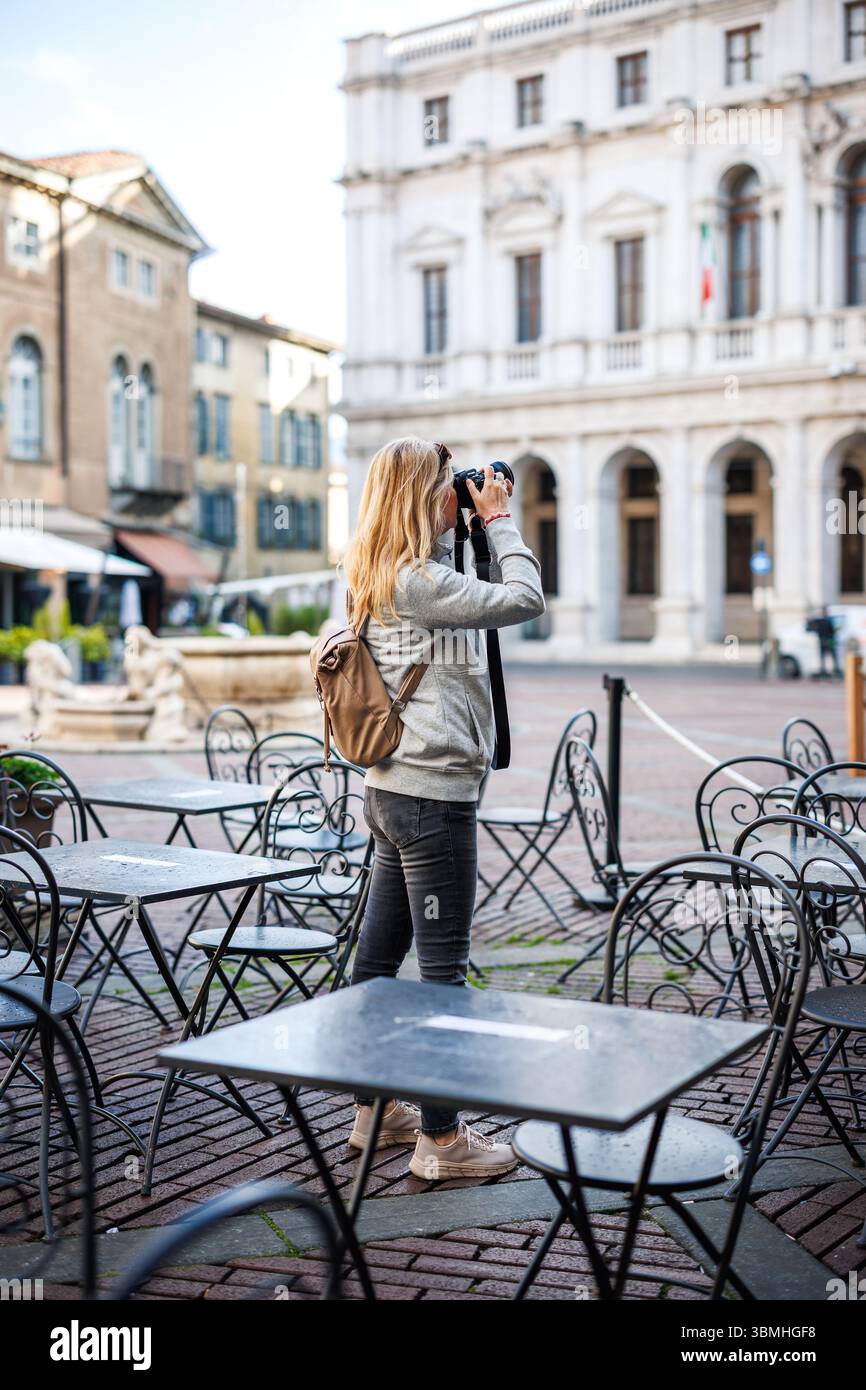 Tourist woman with camera capturing street scene in Bergamo, Italy ...