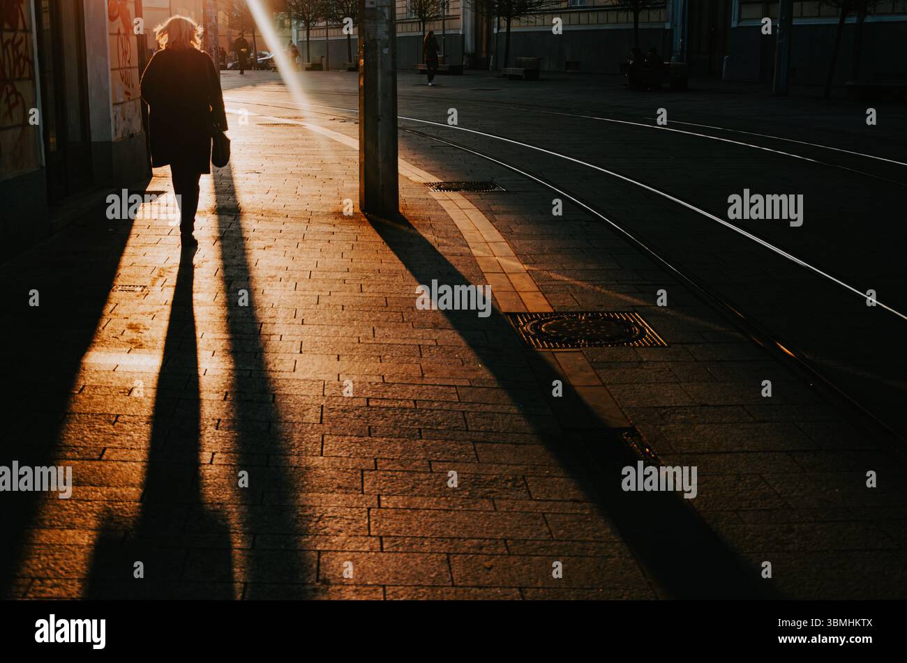 Silhouette of a pedestrian walking through city streets under evening ...