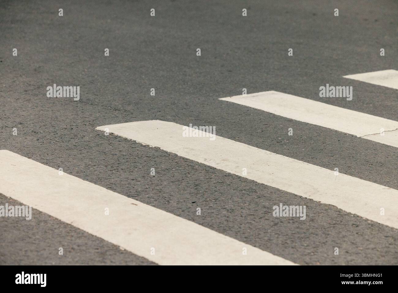 White road markings indicating pedestrian crossing on asphalt surface ...