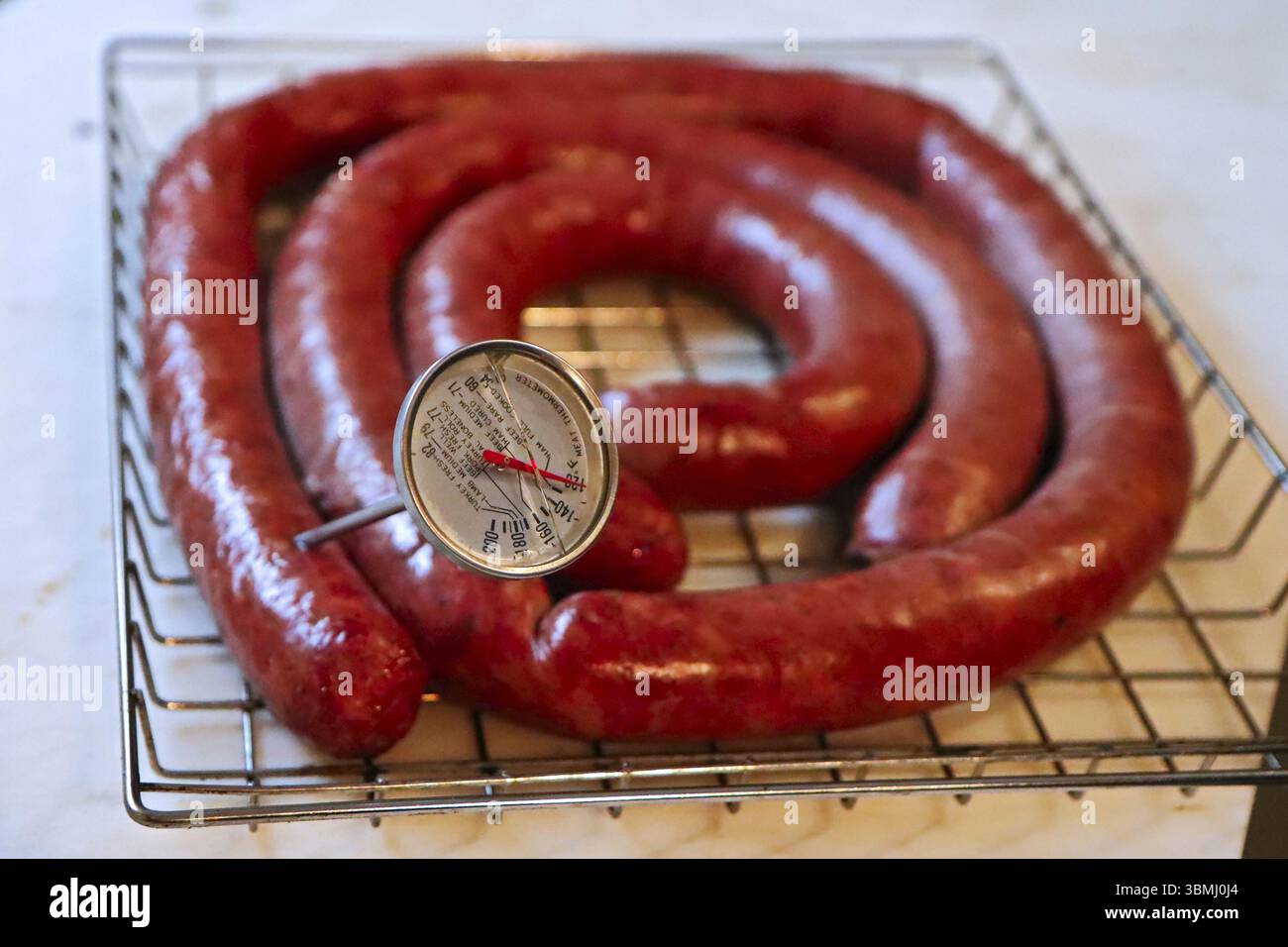 A coil of Kobasa on a cooling rack with a thermometer Stock Photo - Alamy