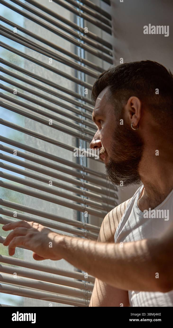 Glam shadows. Man sits in partial light, shadow lines from blinds ...