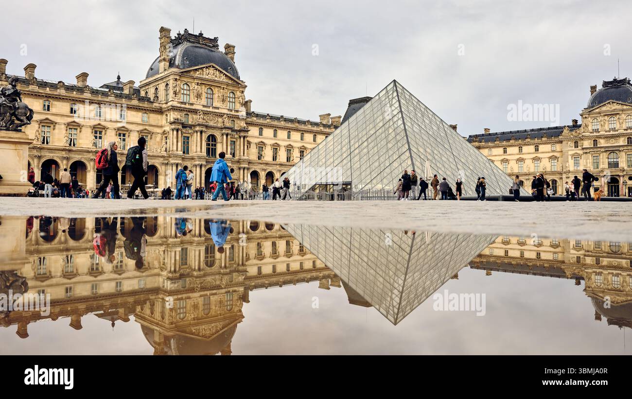 Louvre museum and pyramid reflecting in puddle after rain in paris ...
