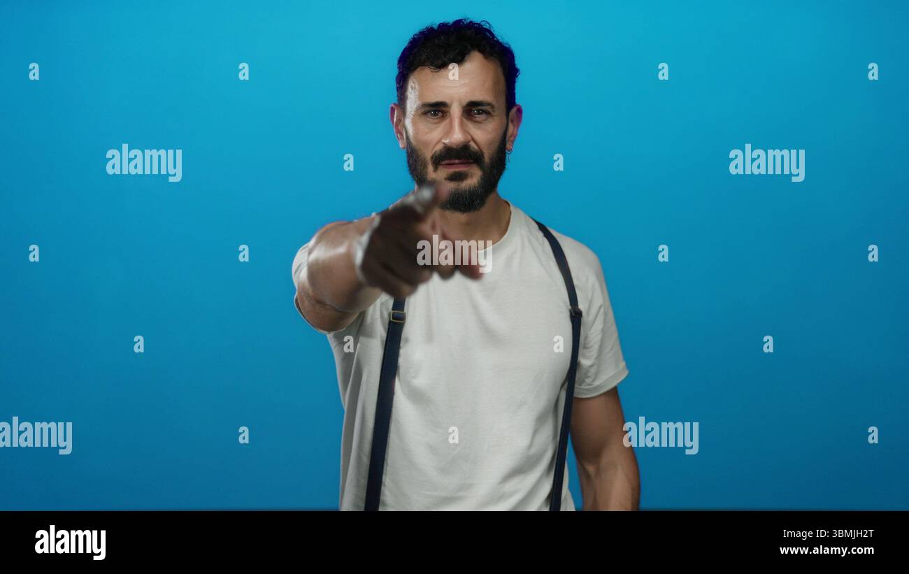 Hispanic man with beard pointing forward in blue background wearing ...