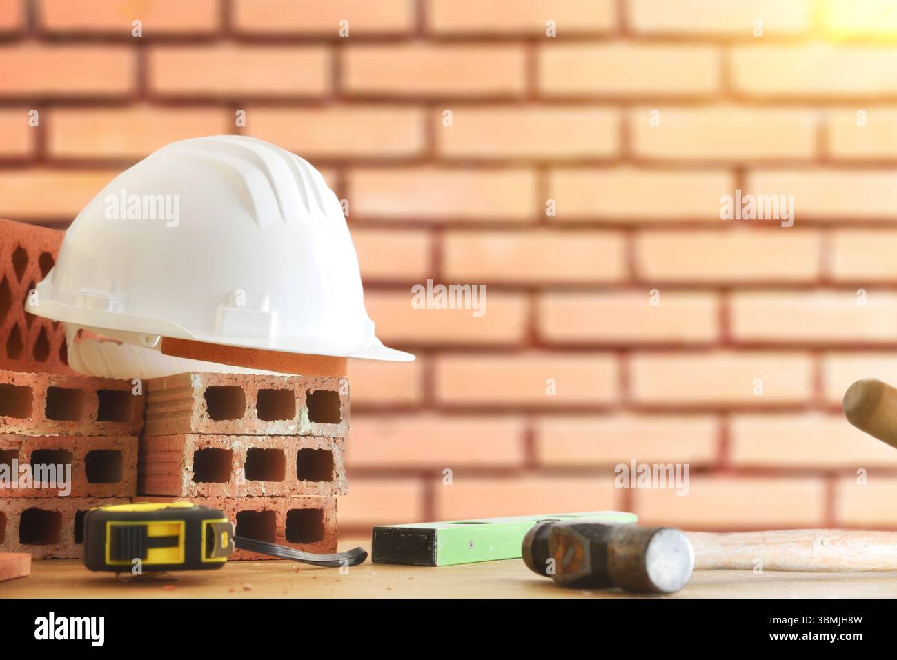 Stack of bricks and protective helmet on top on wooden plank with tools ...