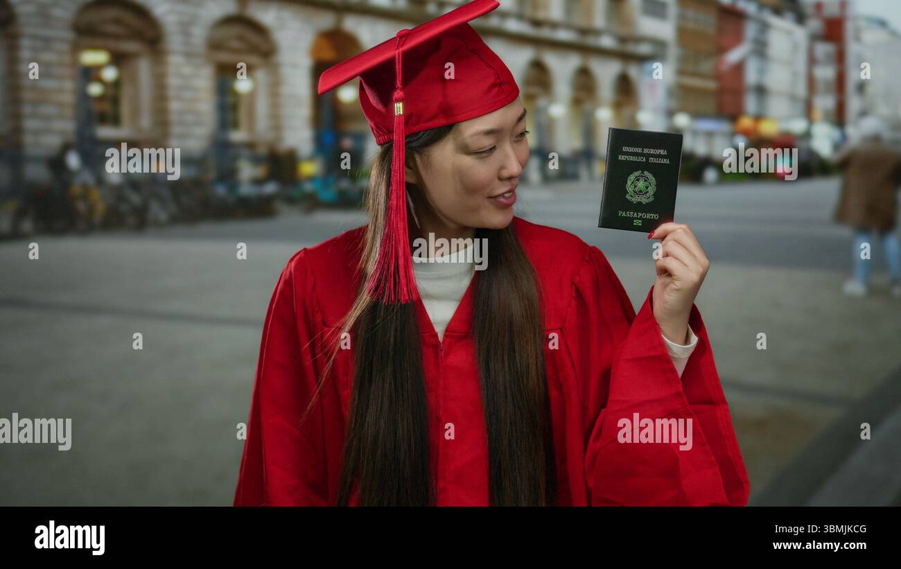 Woman in red graduation gown holding italian passport on city street ...