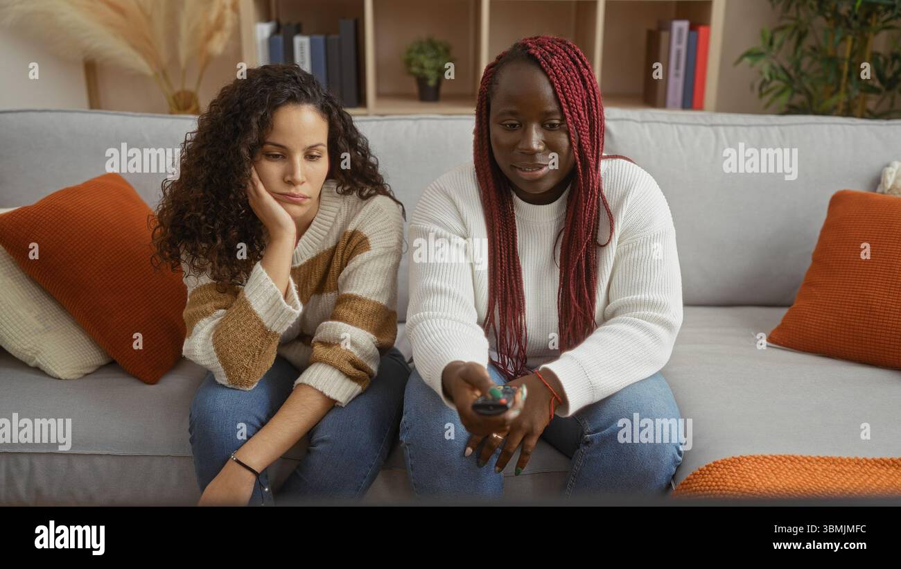 Two young women relaxing at home in a cozy living room, sitting on a ...