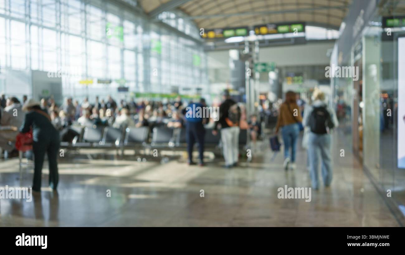 Blurred travelers walking through a busy airport terminal with sunlight ...