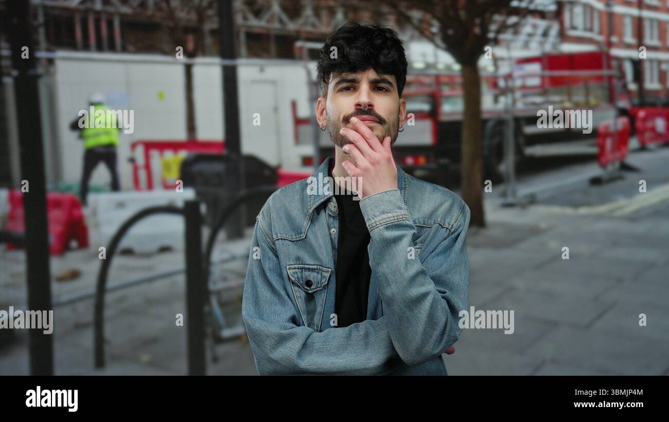 Young man standing confidently at an outdoor construction site, wearing ...