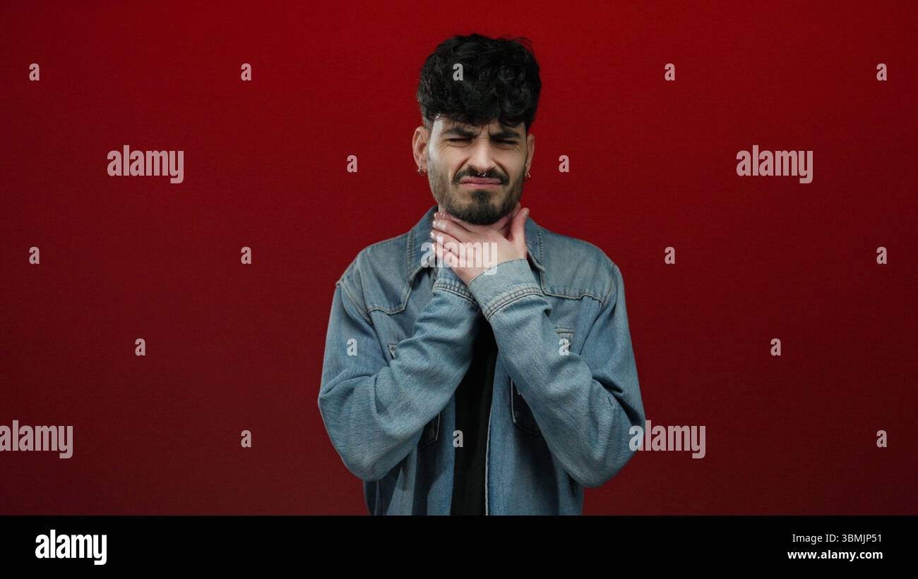 Young man isolated against red background appears distressed placing ...