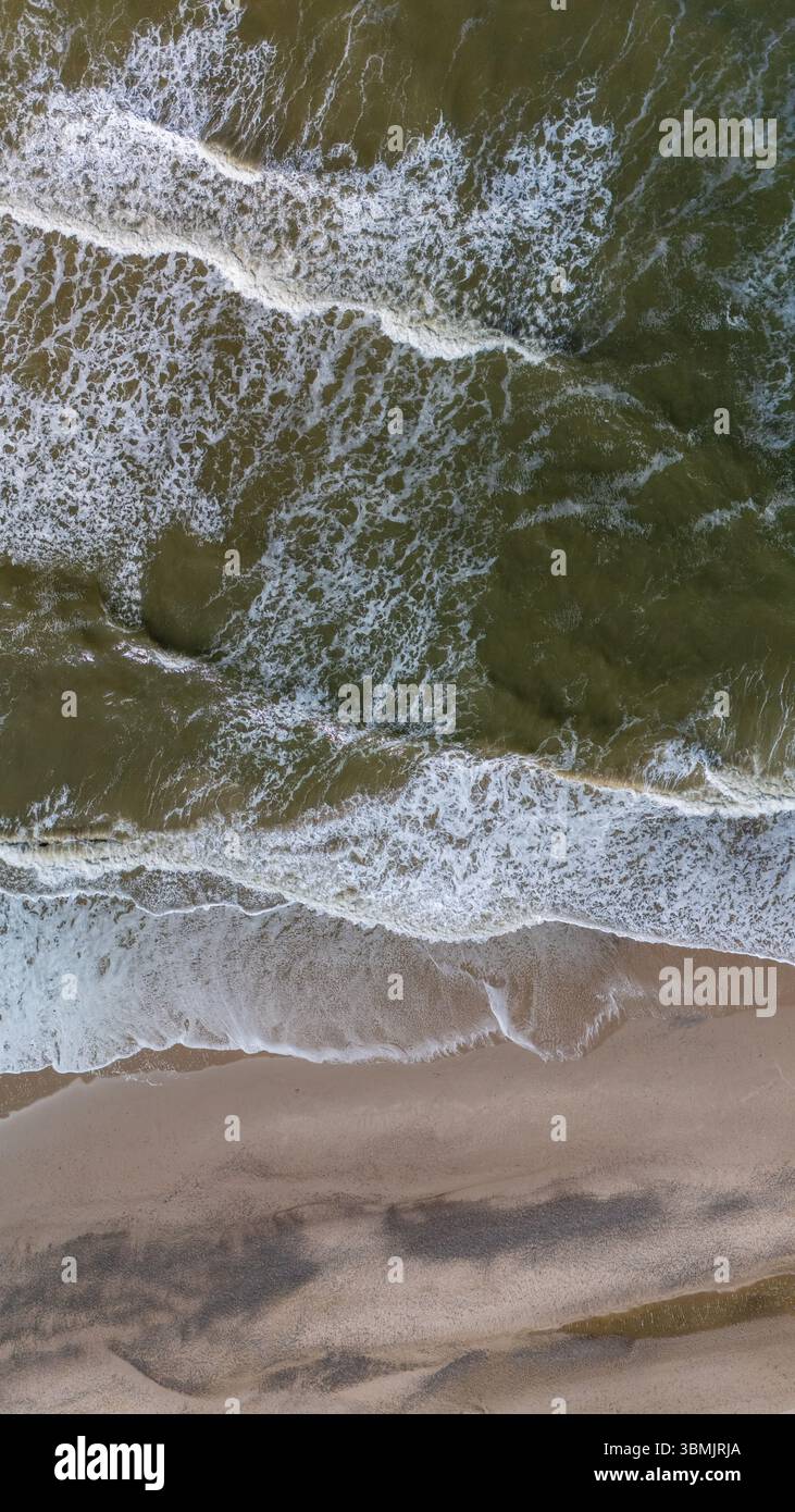 Aerial view captures gentle waves lapping against the sandy beach in ...