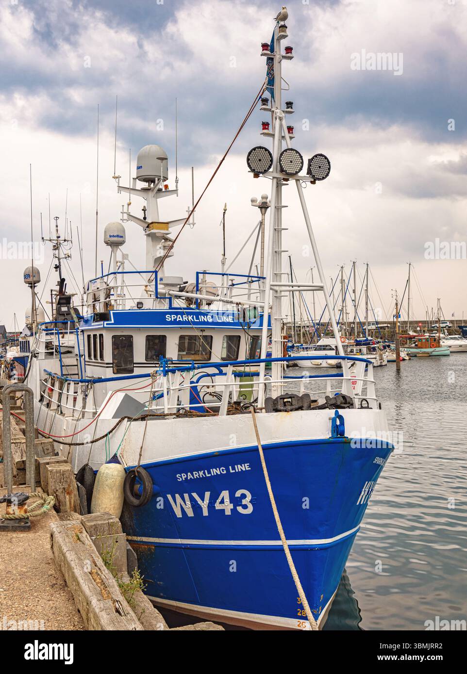 A trawler is moored alongside a quay and a pier and the yachts of a ...