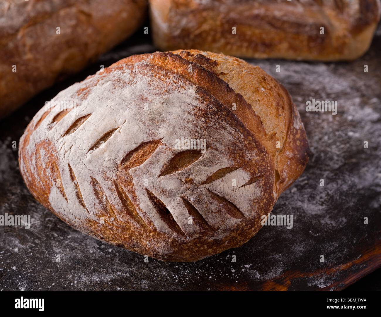 Close-up of a loaf of sourdough artisan bread with two loaves in the ...