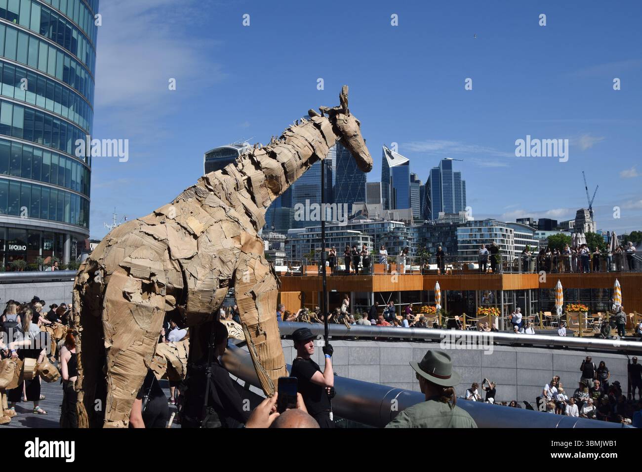 London, UK. 27th June 2025. Puppeteers take a life-size giraffe puppet ...