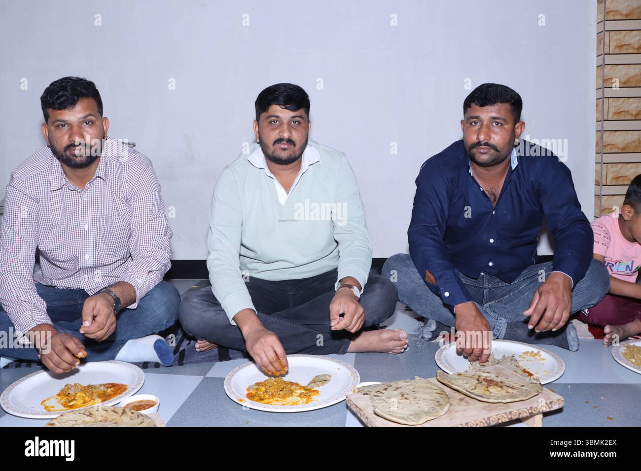 Trio of Indian men seated on the ground with thali plates during a ...