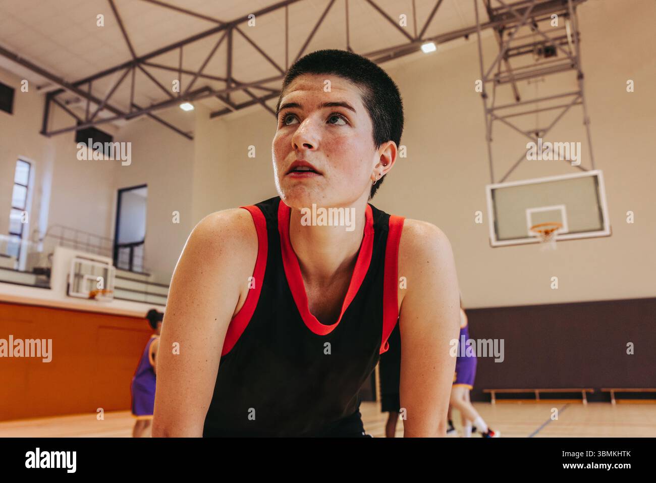Focused female basketball player rests and catches her breath on an ...