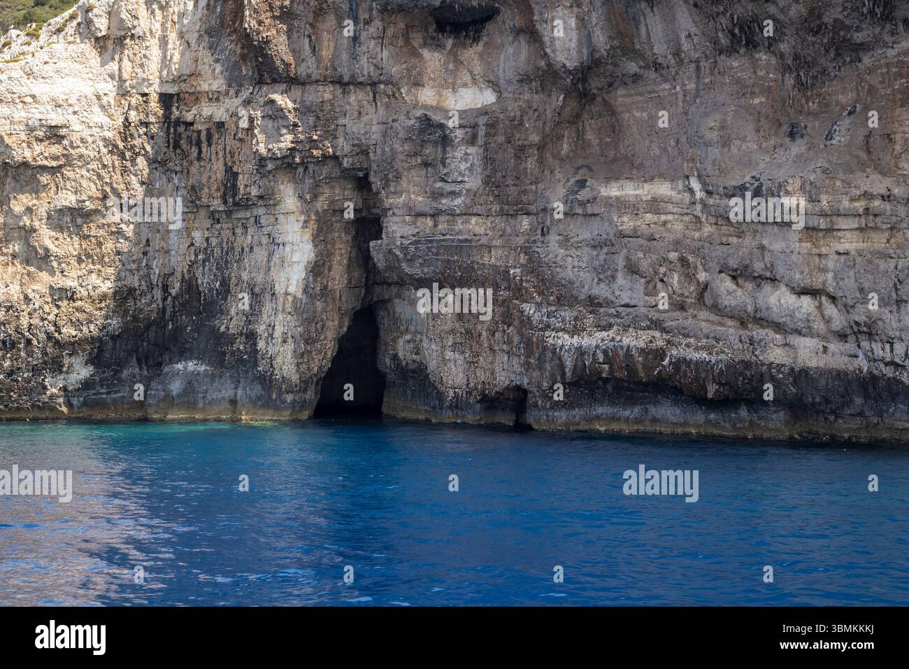 dramatic sea cave, towering cliff, deep blue water, rugged coastline ...