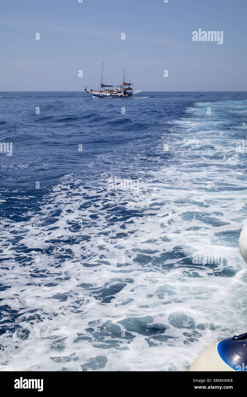 serene blue ocean with distant sailing ship and boat wake under clear ...