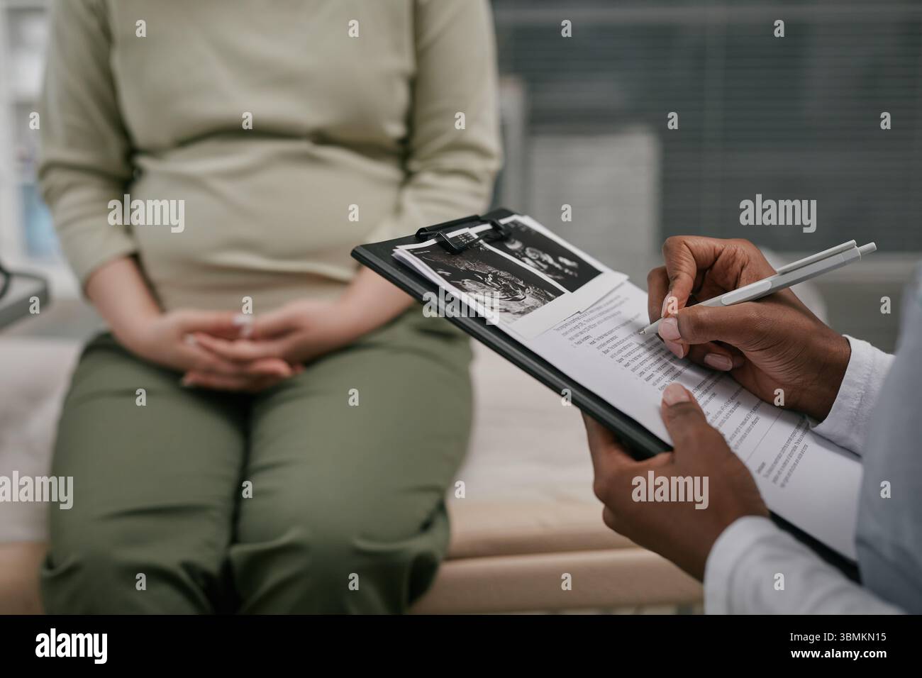 Pregnant woman sitting on examination table during prenatal checkup ...