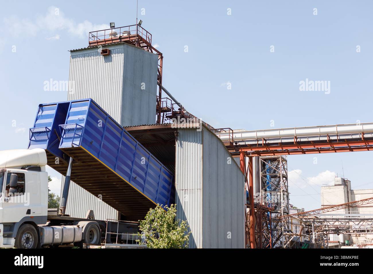 Truck unloading grain at elevator facility with modern silos and ...
