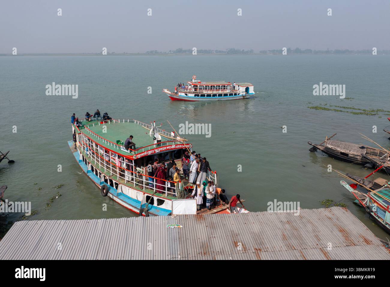 A small passenger launch anchors at the riverside jetty of Baishmouja ...