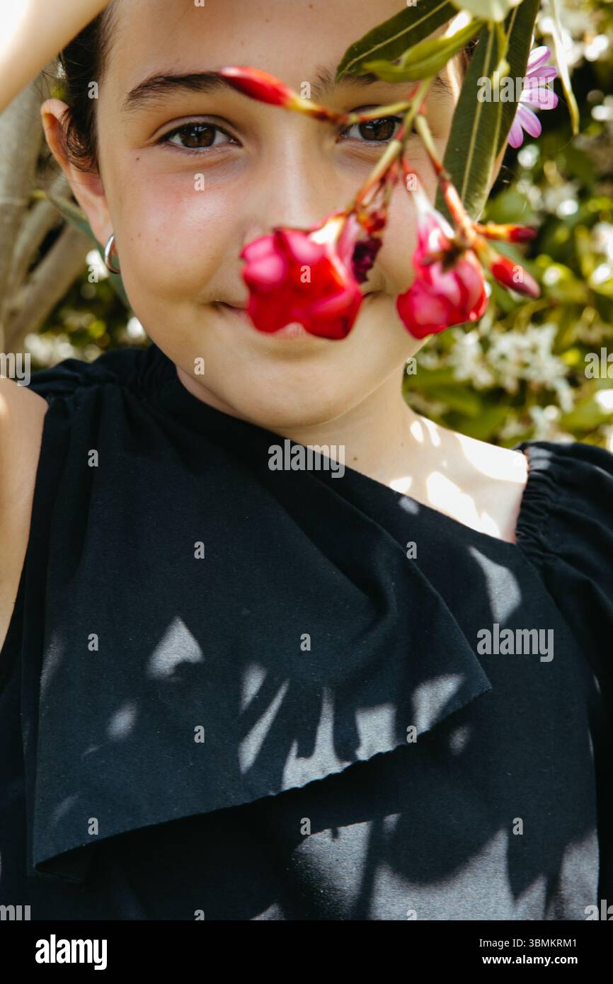 Portrait of a girl smiling behind red flowers in natural light Stock ...