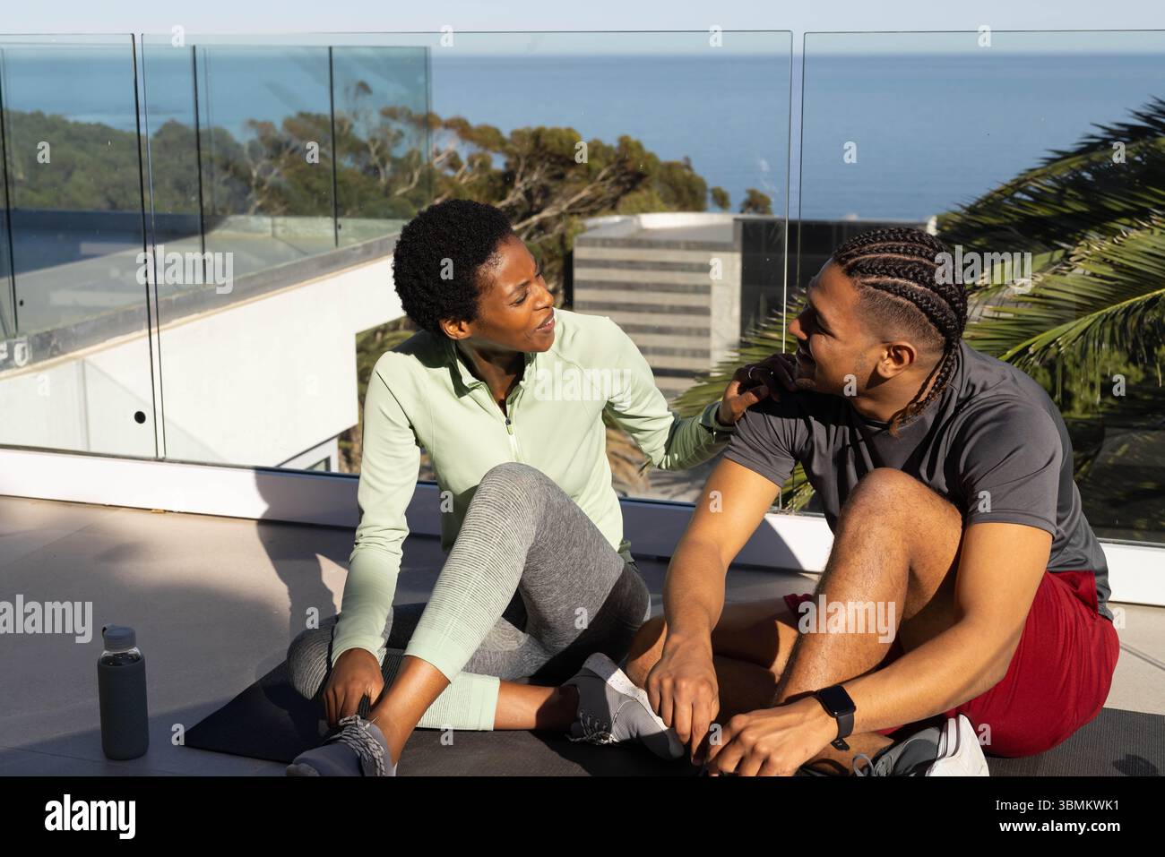 Talking couple sitting on rooftop terrace overlooking ocean, with yoga ...