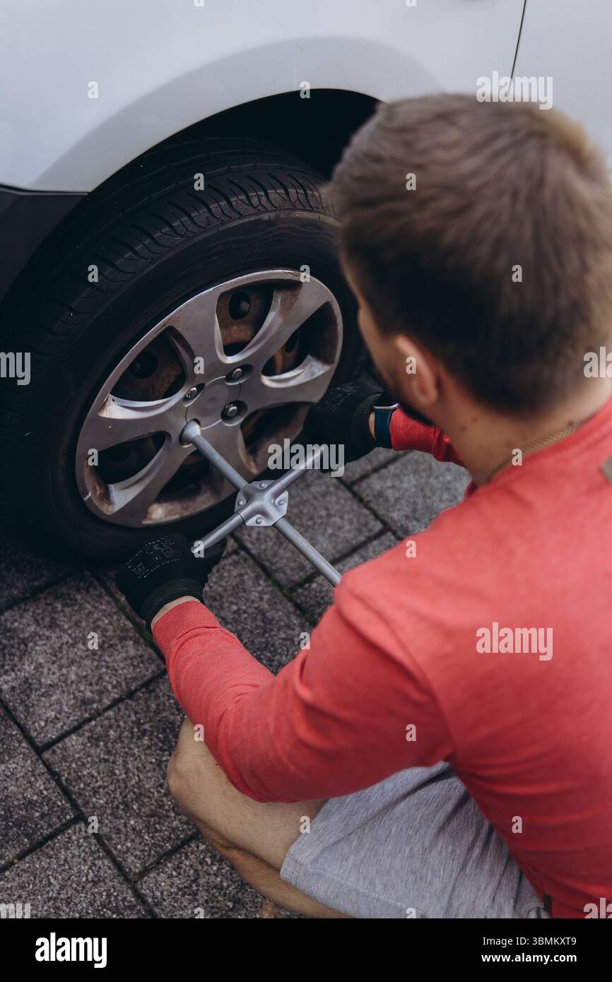 Man changing car tire on roadside using tools, vehicle lifted on jack ...