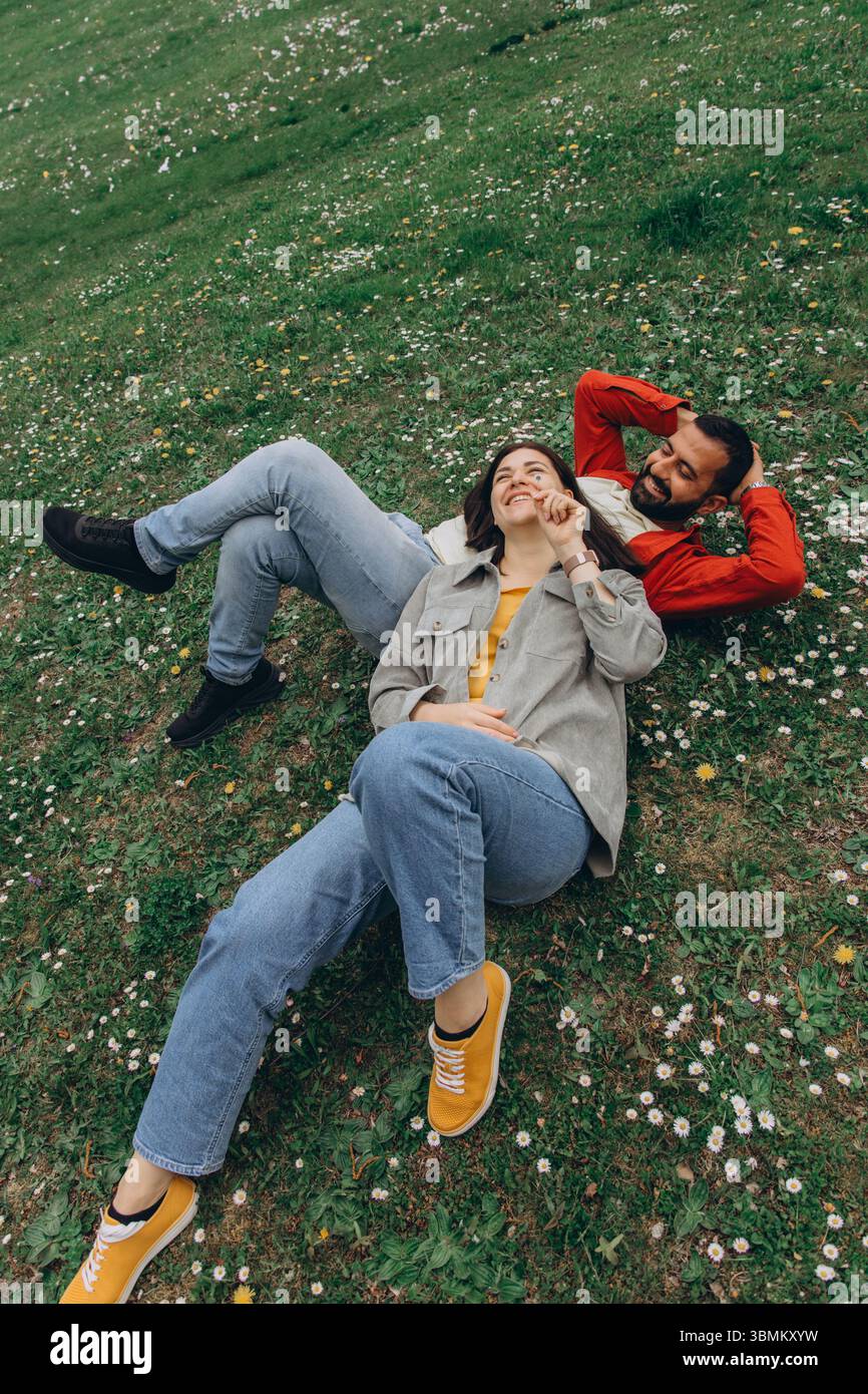 Two people,woman and man relaxing together on grassy field with small ...
