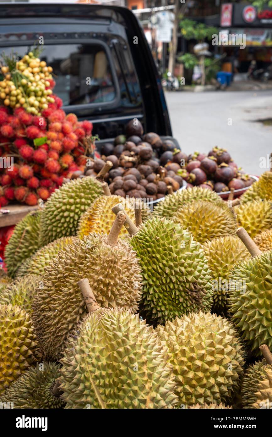 Pile of durians are on display at a market. The durians are piled high ...