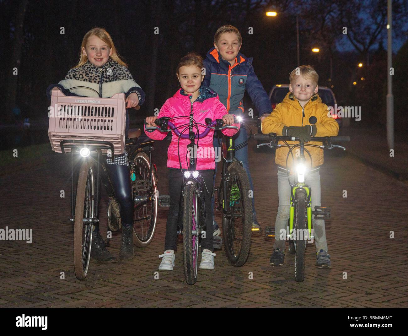 Netherlands, children on bicycles with their headlights and taillights ...
