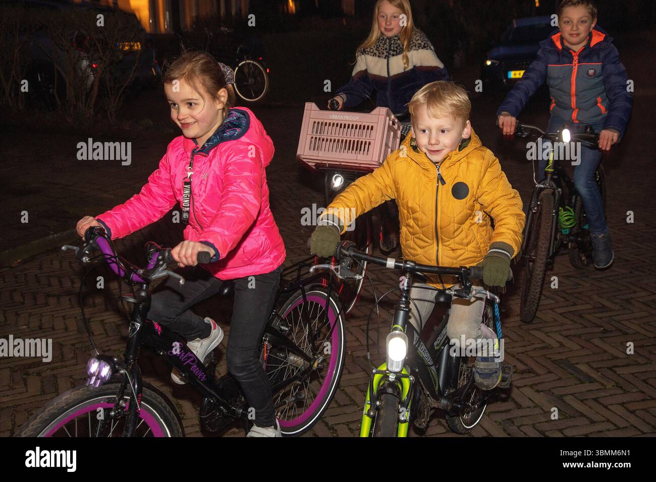 Netherlands, children on bicycles with their headlights and taillights ...