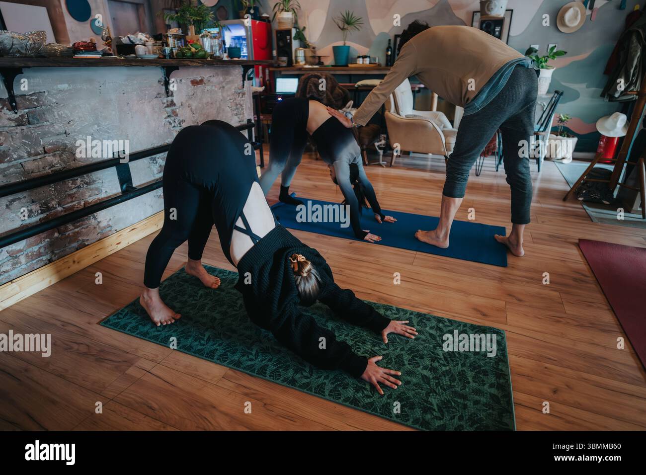 Yoga students practicing poses indoors with an instructor guiding Stock ...