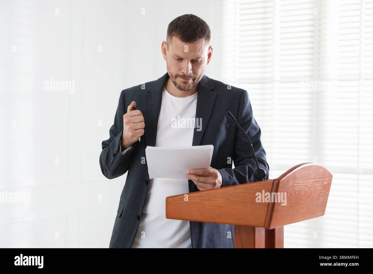 Fear of public speaking. Nervous man with microphone at lectern indoors ...