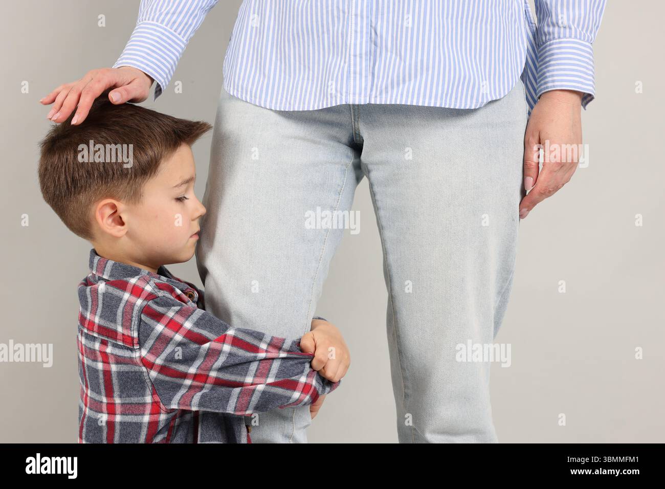 Little boy afraid to leave without mother and hugging her on grey ...