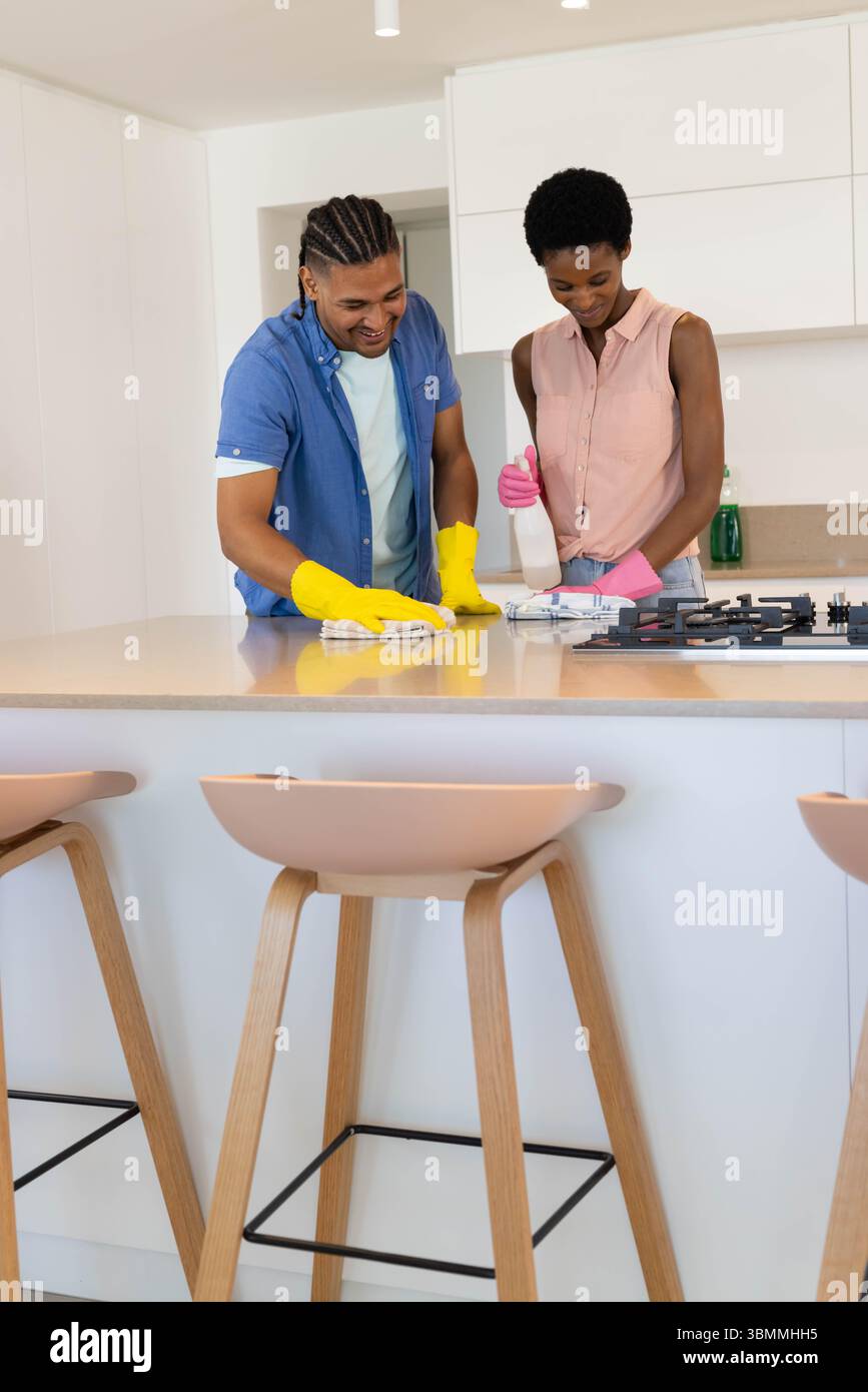 Cleaning African American couple wiping down kitchen island at home ...