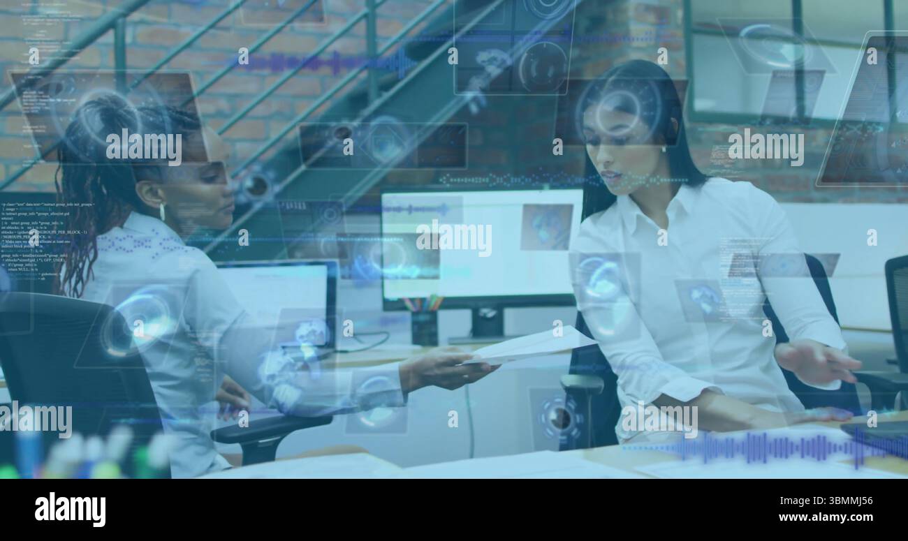 Two women colleagues handing document and reviewing code on monitors in ...